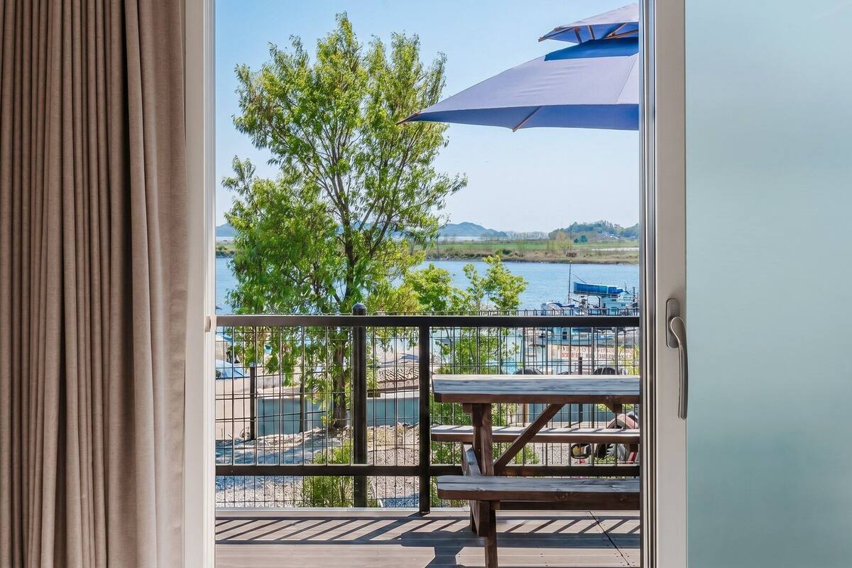 Uma varanda com vista para um lago, árvores e colinas ao longe.