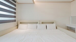 Quarto com cama, almofadas, mesa de cabeceira e espelho.