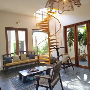 Uma sala de estar moderna com uma escada em espiral, um sofá, uma mesa de centro e uma poltrona.