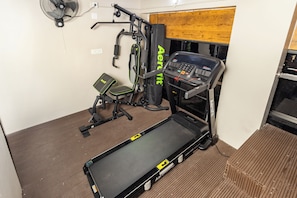Uma academia compacta com esteira, banco de musculação e equipamentos de ginástica.