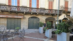 Uma área de café ao ar livre com mesas e cadeiras, um edifício com porta fechada e um letreiro de gelateria.