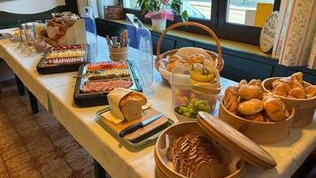 Uma mesa de buffet com diversos alimentos, incluindo pão, frutas e carnes.