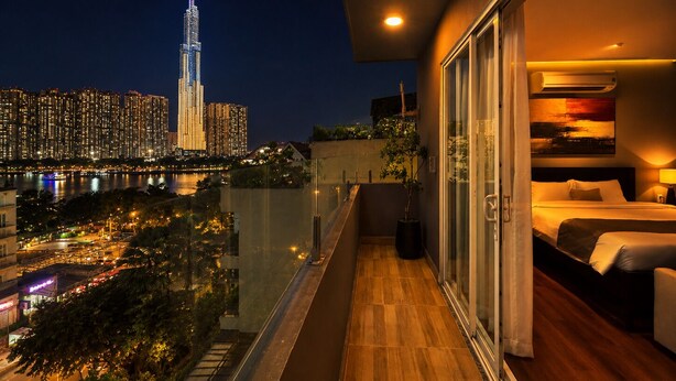 Varanda com vista para a cidade, uma cama e céu noturno.