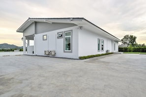 Uma casa moderna térrea com telhado plano, grandes janelas e varanda coberta.