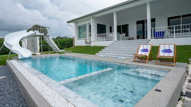 Piscina com escorregador, alpendre coberto e área de estar externa.