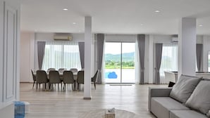 Uma sala de estar moderna com área de jantar, janelas amplas e vista para o exterior.