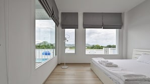 Quarto com cama, duas janelas, vista para uma piscina e varanda.