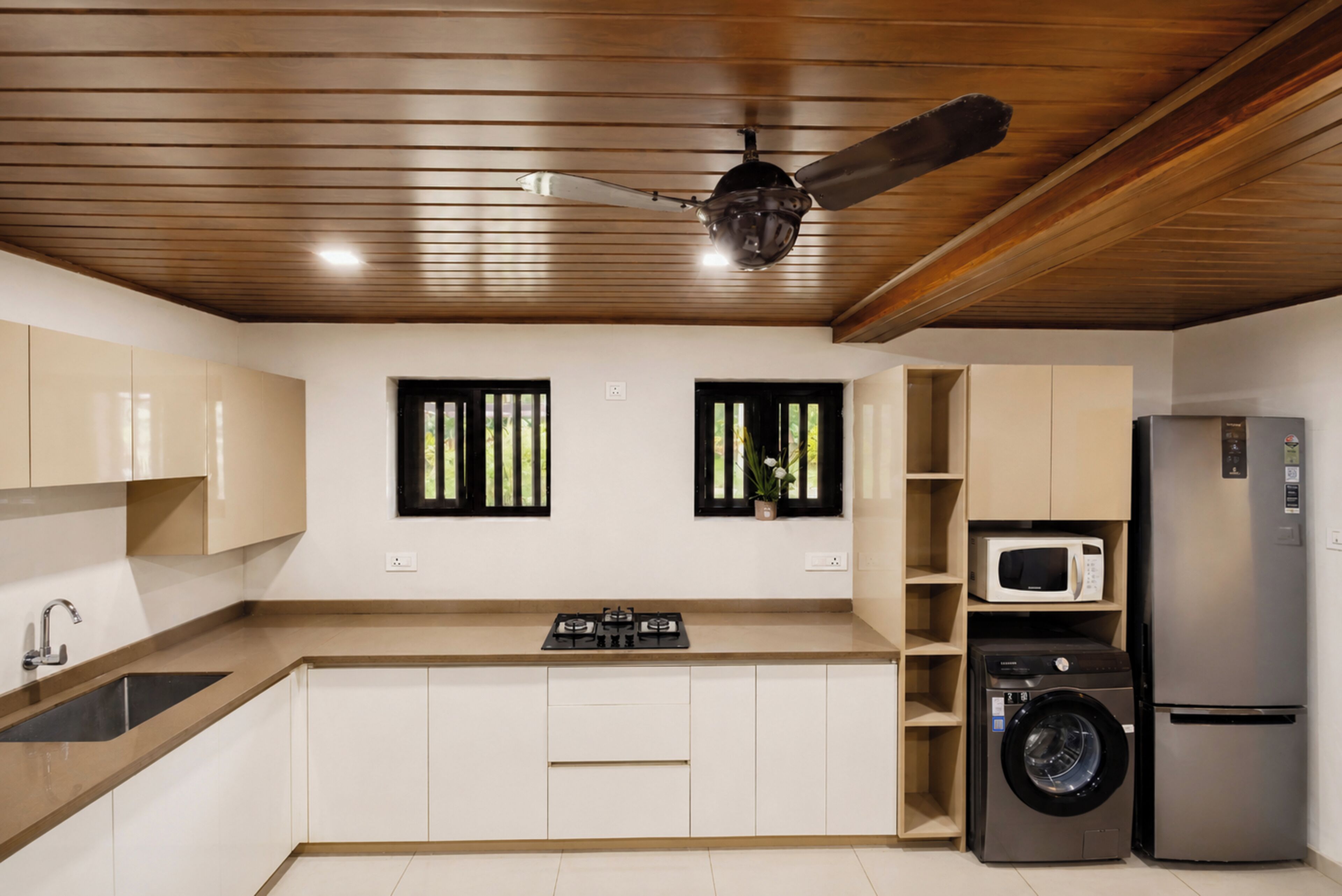 Uma cozinha moderna com micro-ondas embutido, geladeira de aço inoxidável, fogão a gás e ventilador de teto.