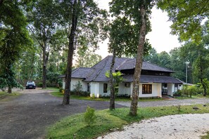 Uma casa com telhado de telhas, cercada por árvores e uma entrada por meio de um caminho.