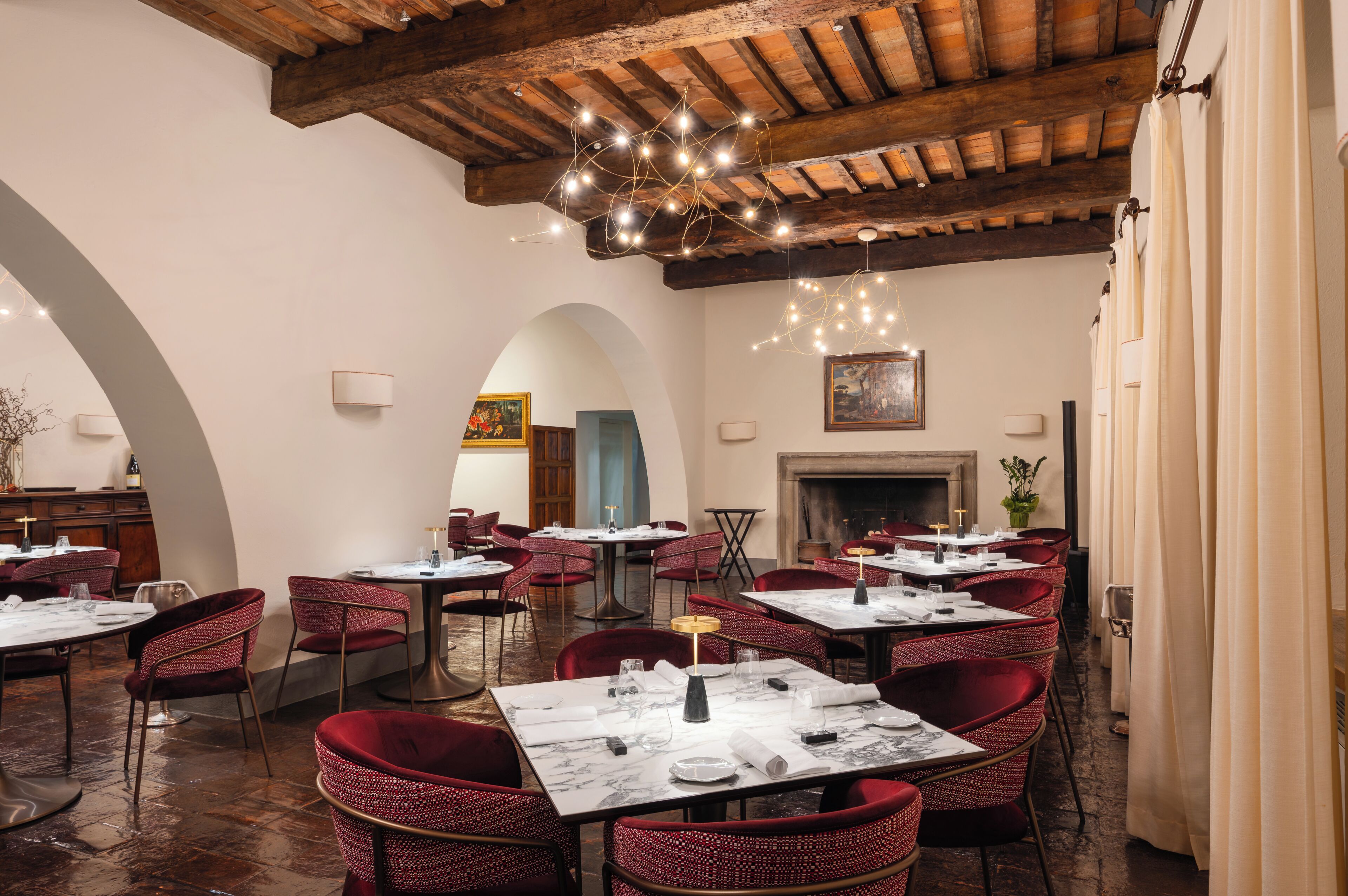 Um restaurante com várias mesas e cadeiras, teto de madeira e lareira.