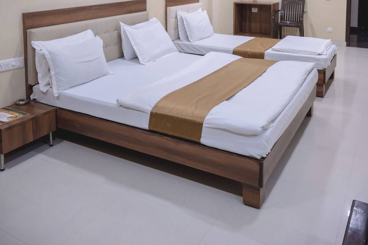 Quarto de hotel com duas camas, um ventilador de teto, obras de arte nas paredes e uma mesa de cabeceira com abajur.