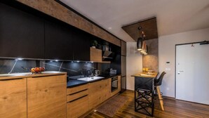 Uma cozinha moderna com armários de madeira, bancada preta e um espaço de refeições com uma cadeira.
