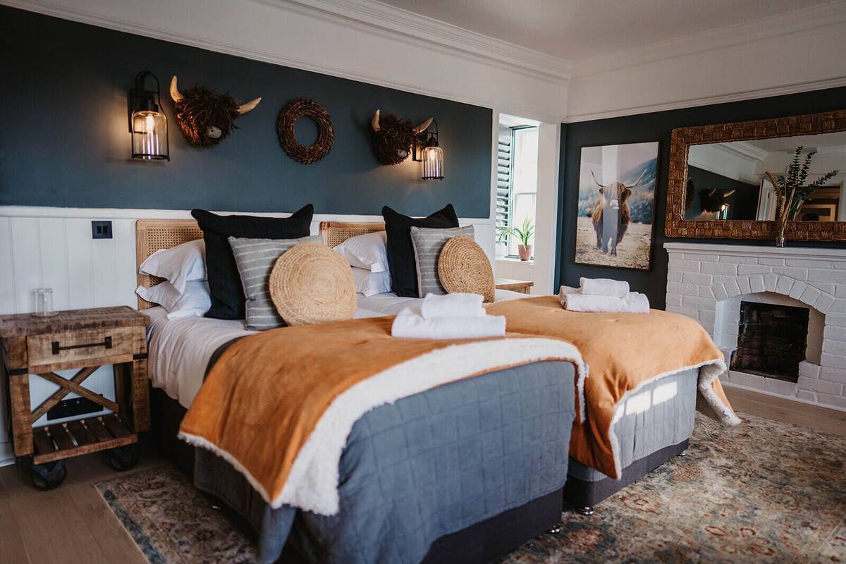 Quarto com uma cama de casal, mesa de cabeceira, lareira e decoração na parede.
