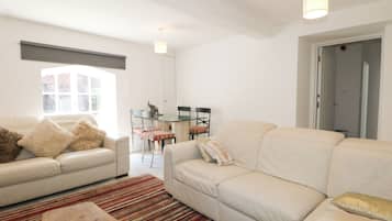 Uma sala de estar com sofá, mesa de centro e mesa de jantar com cadeiras.