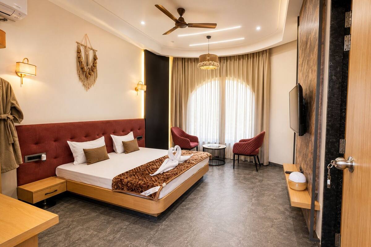 Quarto de hotel com uma cama grande, ventoinha no teto, televisão, uma mesa pequena e duas cadeiras.