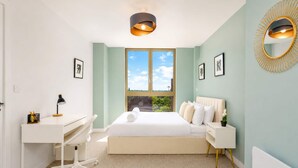 Quarto com cama, escrivaninha e janela.
