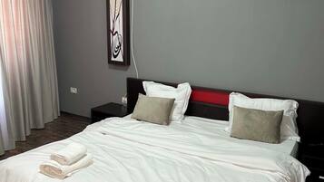Quarto de hotel com uma cama grande, uma mesa de cabeceira, unidade de ar condicionado e uma obra de arte na parede.