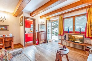 Uma sala de estar aconchegante com lareira, televisão e vista para uma paisagem nevada.