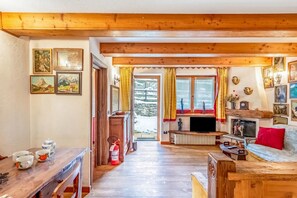 Uma sala de estar aconchegante com vigas de madeira, lareira e vista para uma paisagem coberta de neve.