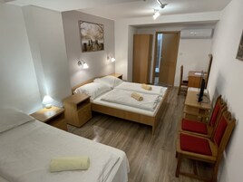 Quarto de hotel com cama, mesas de cabeceira, escrivaninha com cadeira, espelho e um quadro na parede.
