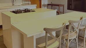 Uma cozinha moderna com uma ilha central, uma mesa de jantar com cadeiras e uma pequena mesa lateral.