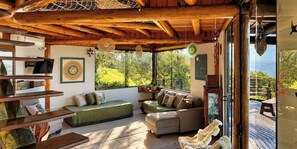 Um interior acolhedor com teto de madeira, um sofá, um banco e vista para o verde lá fora.