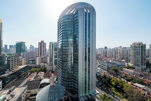 Um edifício alto com fachada curva, rodeado por outros edifícios imponentes em um cenário urbano.