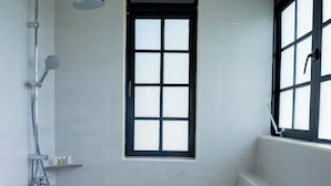 Um banheiro pequeno com revestimento de azulejos, chuveiro, janela e pia.