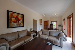 Uma sala de estar com dois sofás de couro, uma mesa de centro de madeira e um quadro na parede.