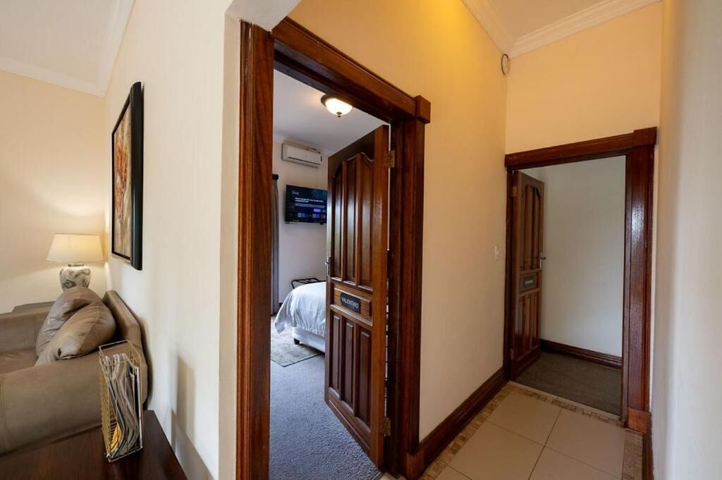Corredor de hotel com uma cama, uma televisão e um abajur.
