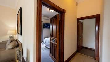Corredor de hotel com uma cama, uma televisão e um abajur.