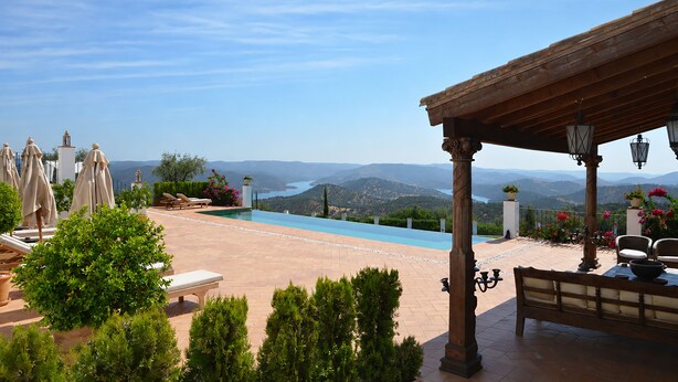 Uma área de piscina com pérgola, espreguiçadeiras e vista para as montanhas.