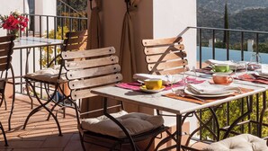 Uma área de refeições ao ar livre com uma mesa posta para dois, cadeiras e vista para um lago.