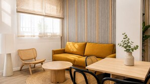 Uma sala de estar moderna com um sofá, cadeiras, uma mesa redonda, uma luminária e uma parede listrada.