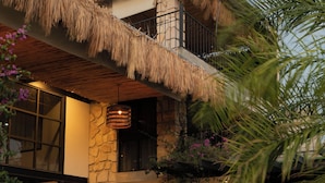Uma casa de dois andares com fachada de pedra, telhado de palha e varanda com grades.
