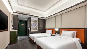 Quarto de hotel com duas camas, televisão, escrivaninha e banheiro.