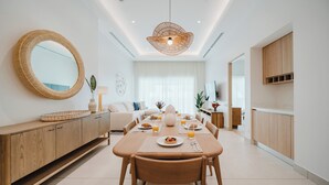 Uma sala de jantar moderna com um espelho redondo, móveis de madeira e uma mesa central com itens de café da manhã.