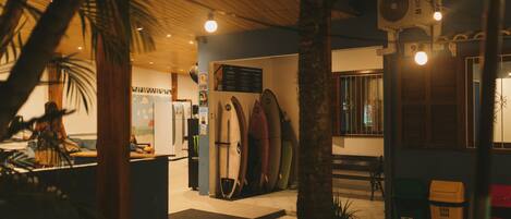 Loja de surf interior com pranchas, teto de madeira e contentores de reciclagem.