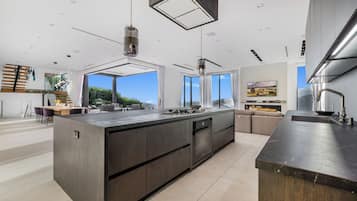 Cozinha moderna com uma ilha grande, eletrodomésticos embutidos e vista para o exterior.