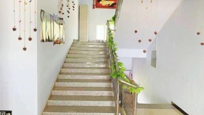 Uma escadaria com corrimão, decorações penduradas e uma placa vermelha na parede.