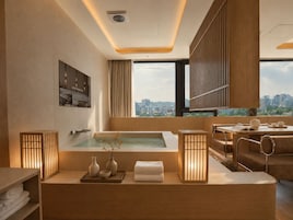 Uma casa de banho moderna com uma banheira, toucador com espelho e vista para a cidade.