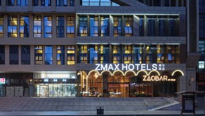 Hotel com fachada moderna, vários andares e entrada imponente com sinalização iluminada.