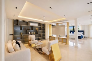 Uma sala de estar moderna com um sofá, poltronas, uma mesa de centro e uma televisão.