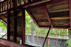 Estrutura de madeira com vista para um muro de tijolos e vegetação.