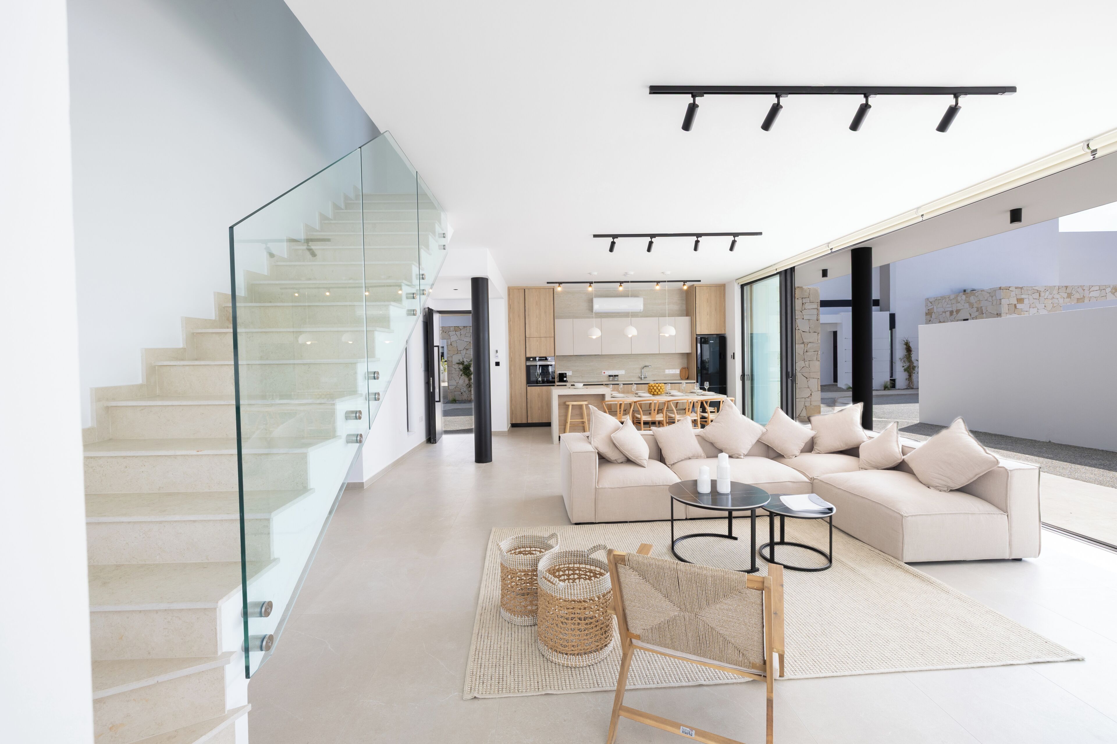 Uma sala de estar moderna com sofá, mesa de centro e escada com guarda-corrimão de vidro.