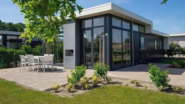 Um edifício moderno com um pátio, área de estar ao ar livre e um jardim bem cuidado.
