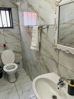 Casa de banho com sanita, lavatório e espelho.