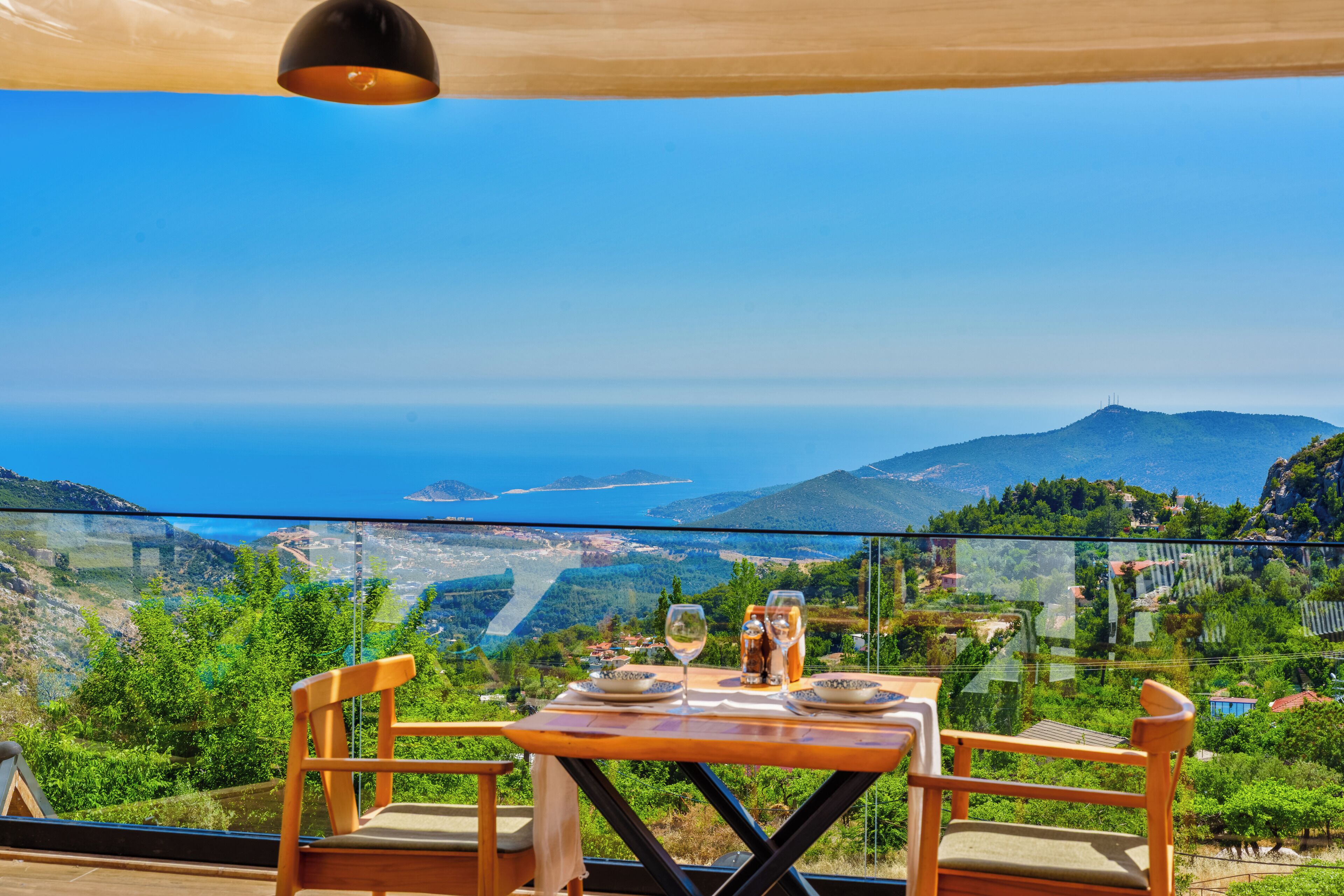 Uma mesa com cadeiras e guarda-corpo de vidro com vista para uma paisagem deslumbrante.