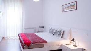 Quarto com cama, mesa de cabeceira, abajur e um quadro na parede.