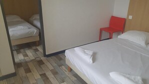 Quarto com uma cama, uma cadeira vermelha e piso de madeira.